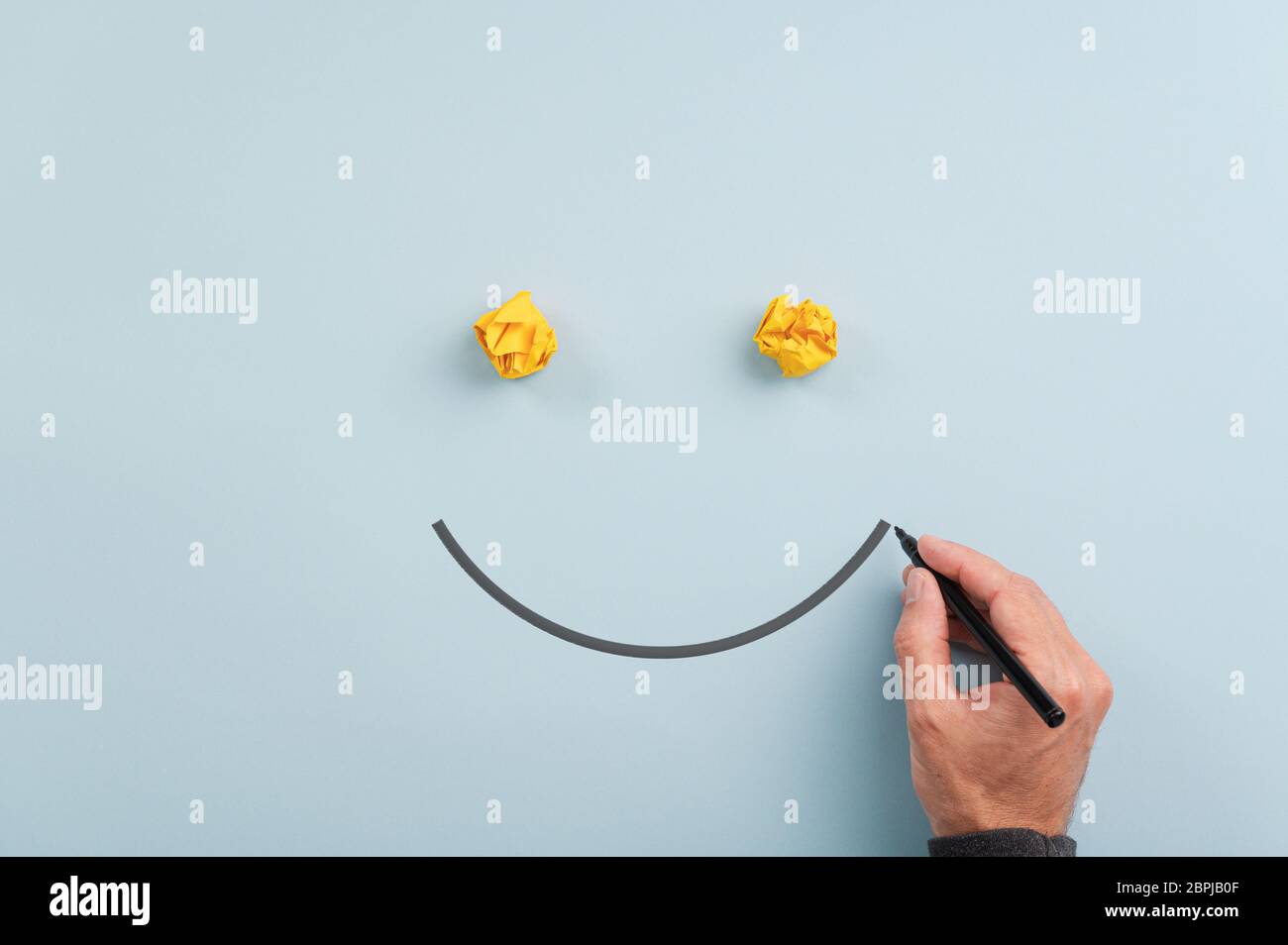 Male hand drawing a smiling face with black marker using crinkled ...