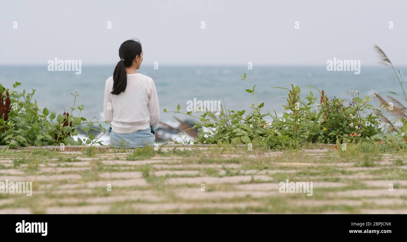 Back view of woman sit down and look at the sea Stock Photo - Alamy