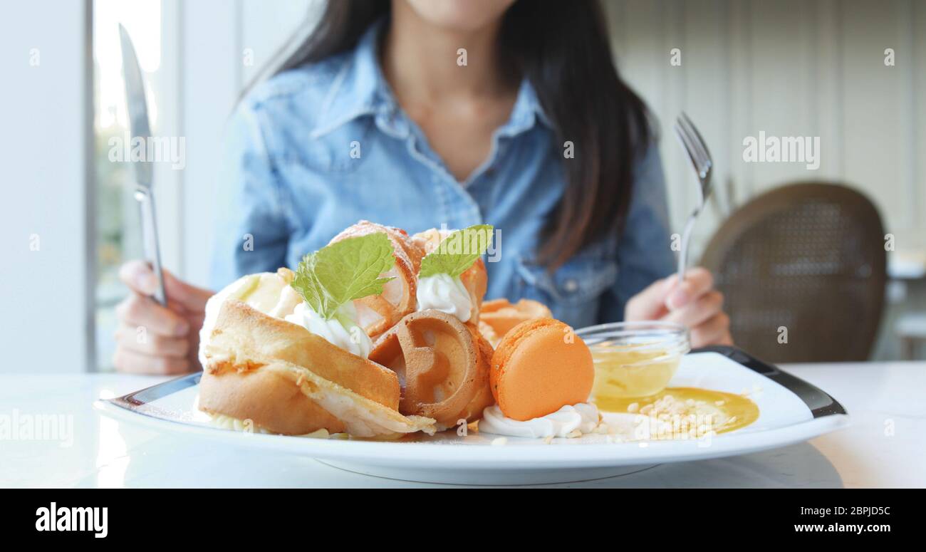 Woman eating waffle in restaurant Stock Photo - Alamy