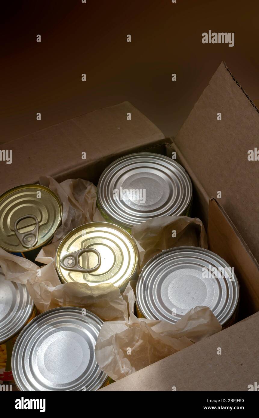 An open cardboard box full of tin cans. Morning rays illuminate a ...