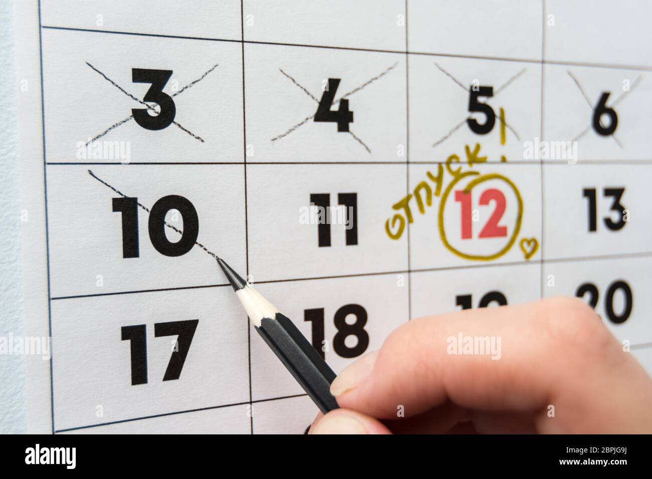 A hand crosses out the penultimate day before the holiday with a pencil ...