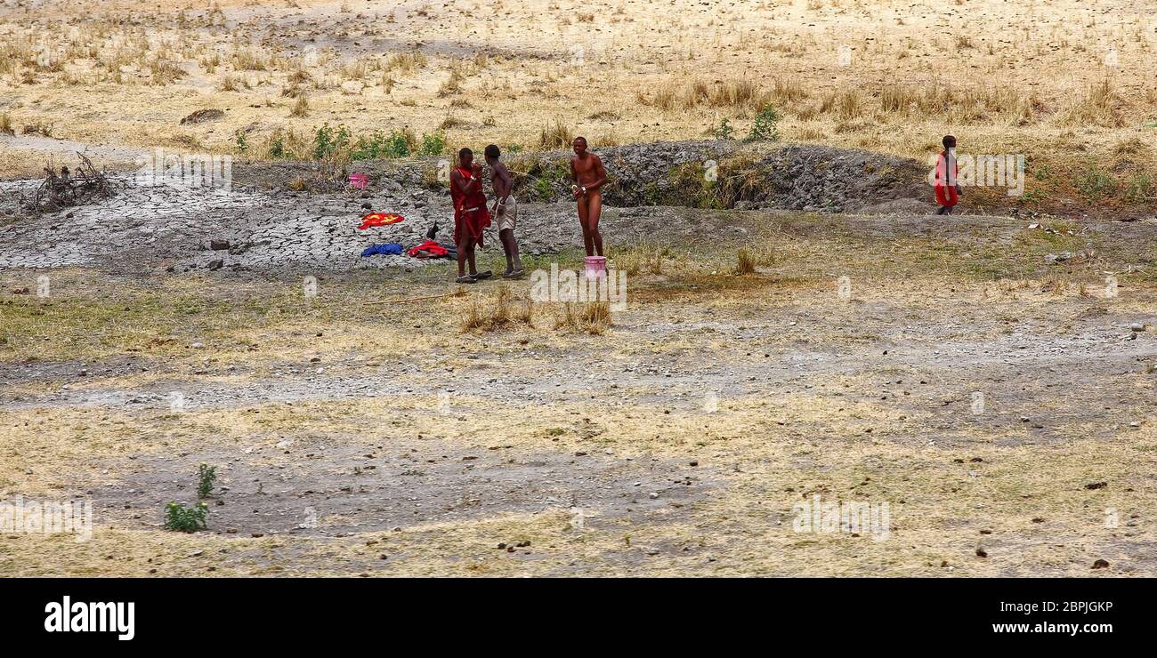 four Maasai young men, shedding clothes, one walking, native tribe ...