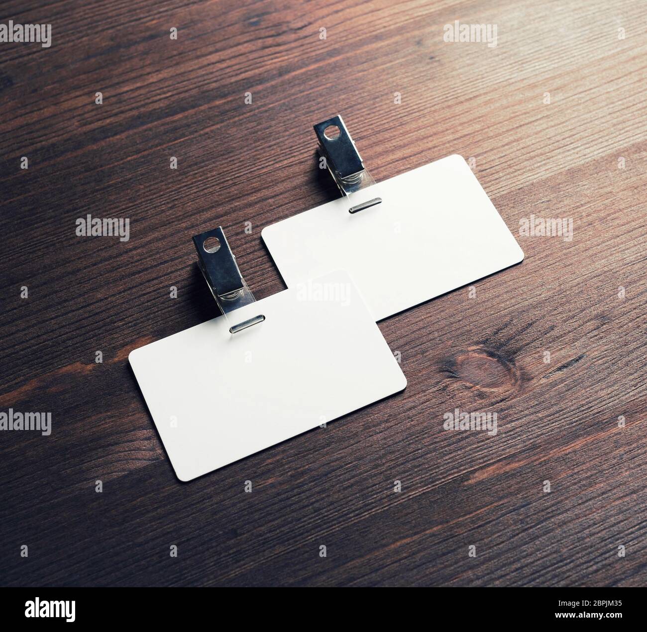 Blank badges mockup on wooden background. Plain empty name tag ...