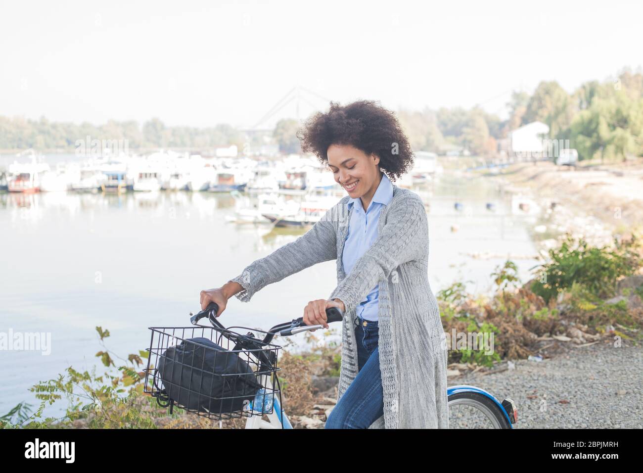 Relaxed Afro woman with bicycle enjoying free time near river Stock ...