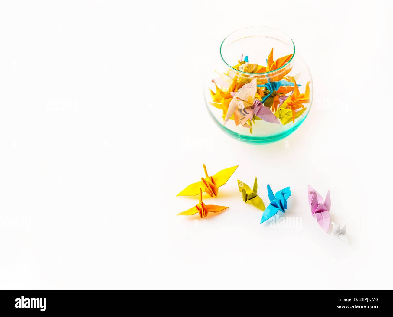 Small origami birds paper on white background and a glass jar filled ...