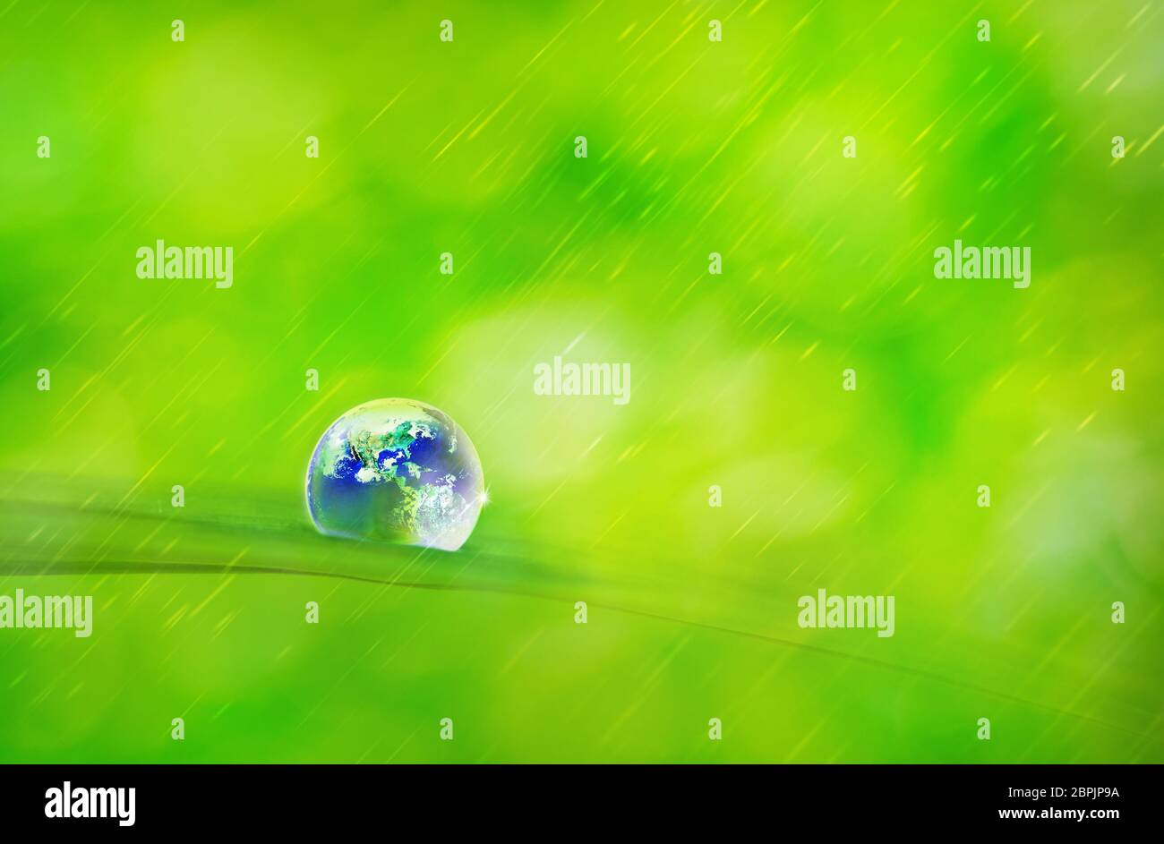 Earth in water drop on green grass with soft bright raining background ...