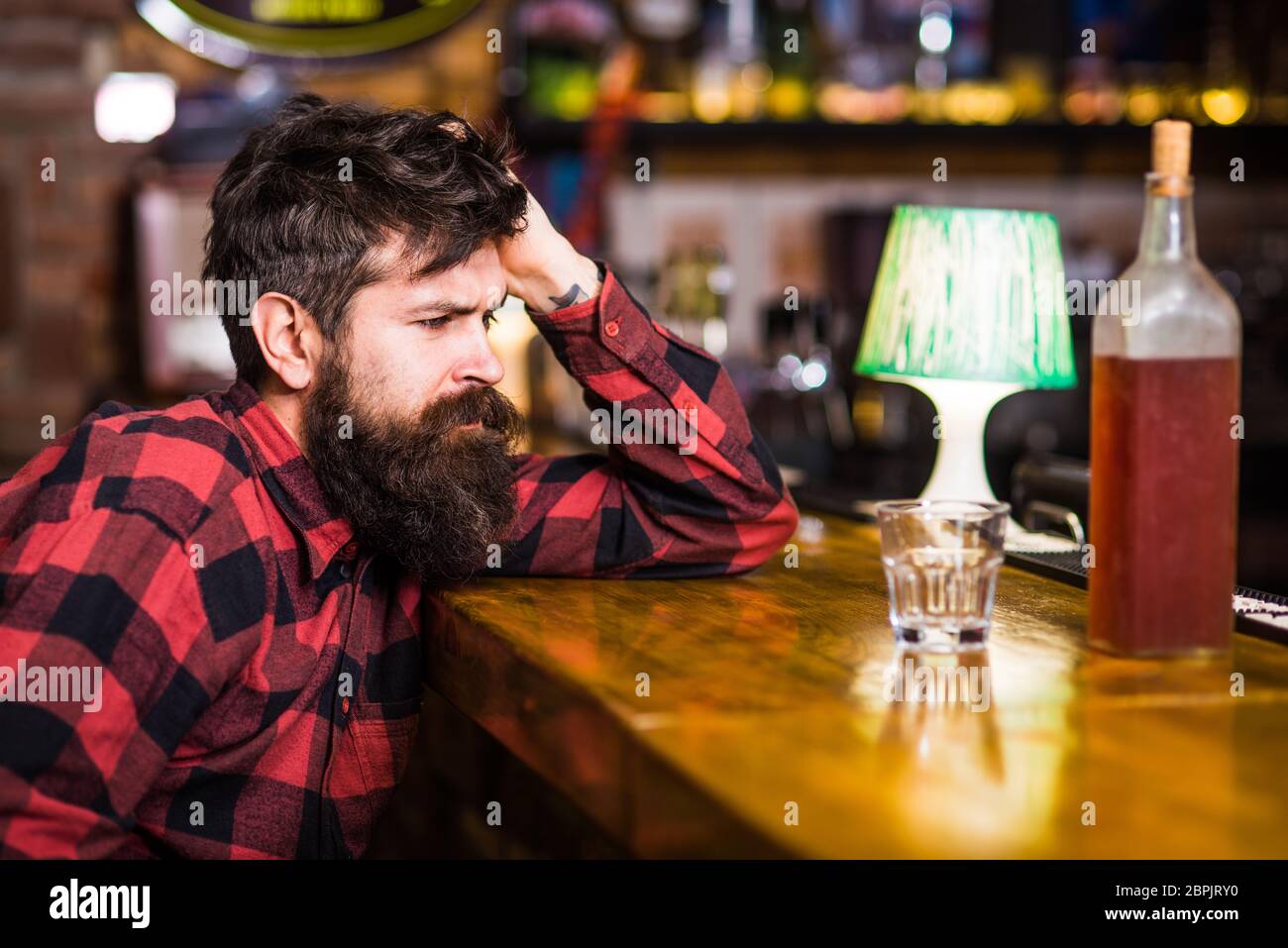 Man with tired face sit in bar or pub near bar counter. Hipster with ...