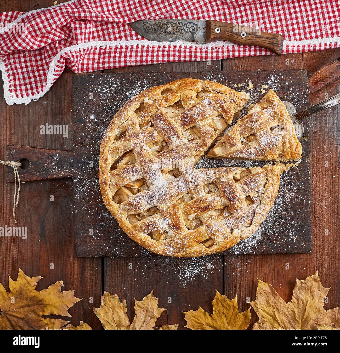 Baked whole round apple pie on a rectangular old brown board, wooden ...