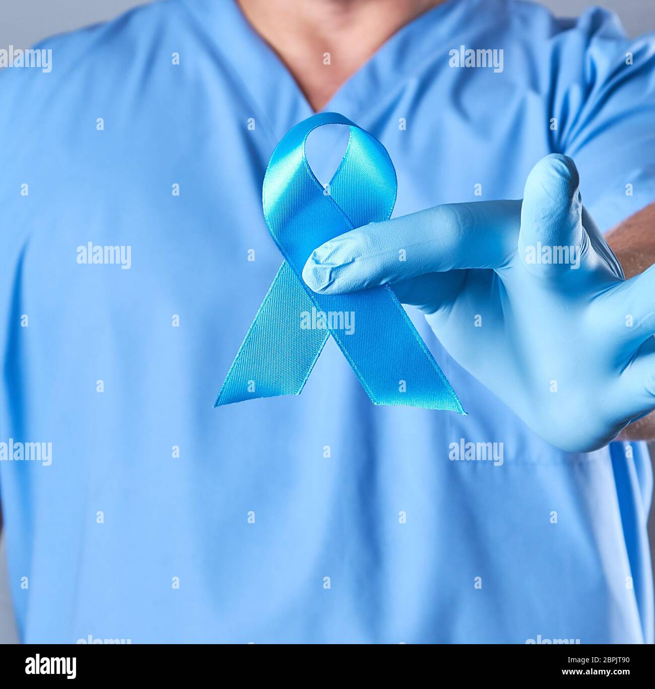 doctor in uniform and latex gloves holding a blue ribbon in his hand ...