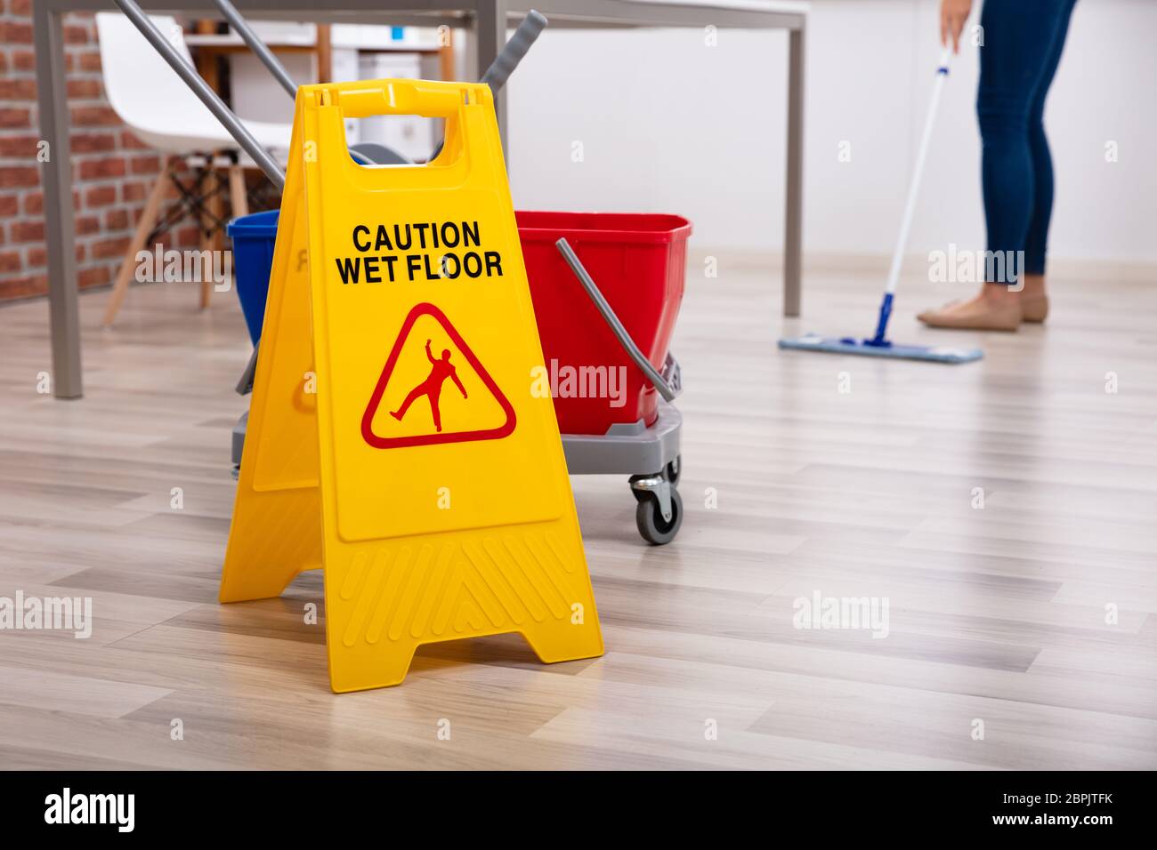 Low Section Of Female Cleaner Standing In Office With Mop And Caution ...