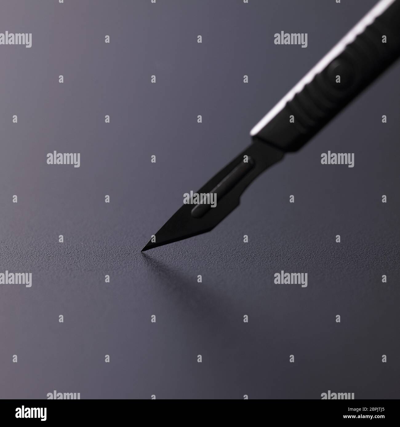Surgical scalpel closeup with blade tip touching grey metallic worktop ...