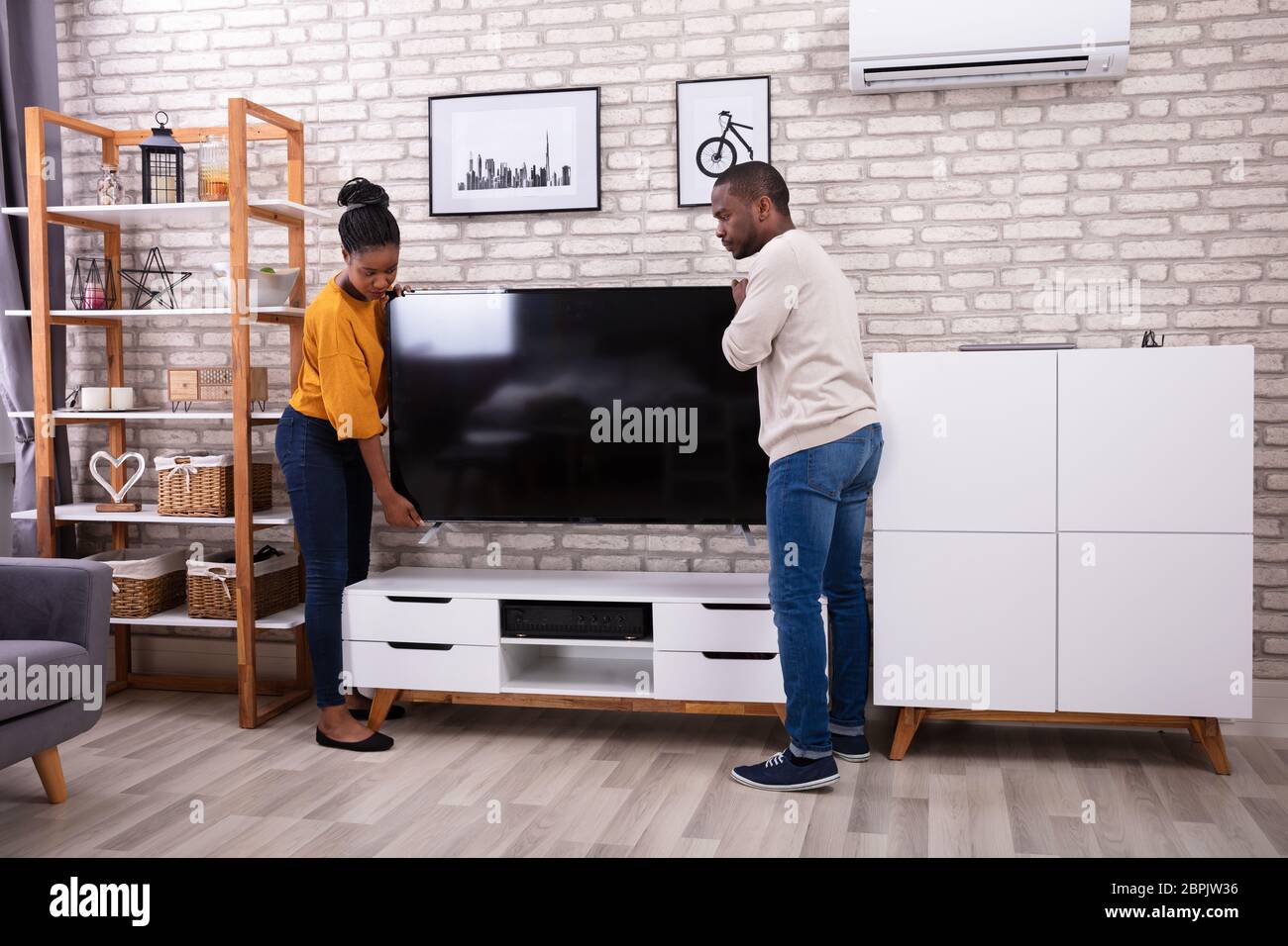 Side View Of Young African Couple Lifting Television At Home Stock ...