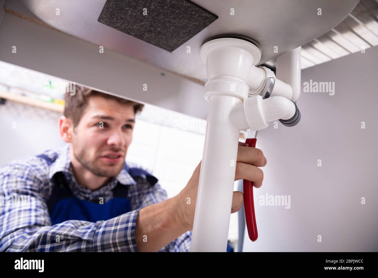 Young Male Plumber Repairing Sink Pipe With Adjustable Wrench Stock ...
