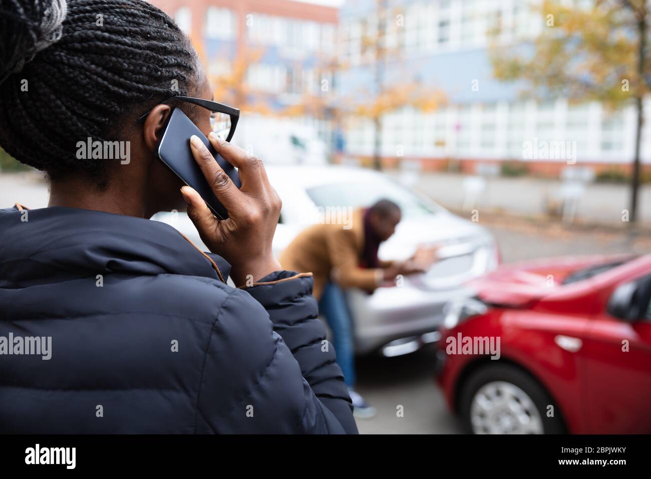 Woman Calling For Assistance In Front Of Man Inspecting Damaged Car On ...
