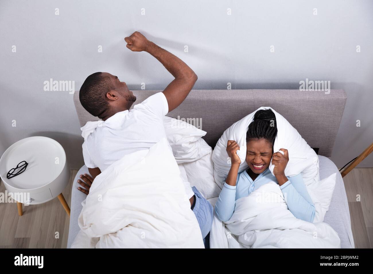 An Overhead View Of Couple Lying On Bed Disturbed By Noise Stock Photo ...