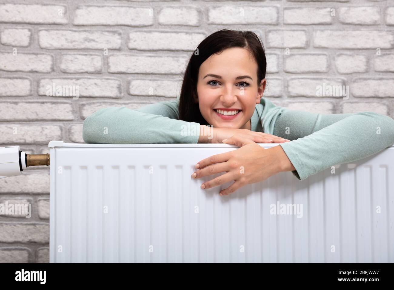 Portrait Of A Happy Young Woman Leaning On Heating Radiator Stock Photo ...