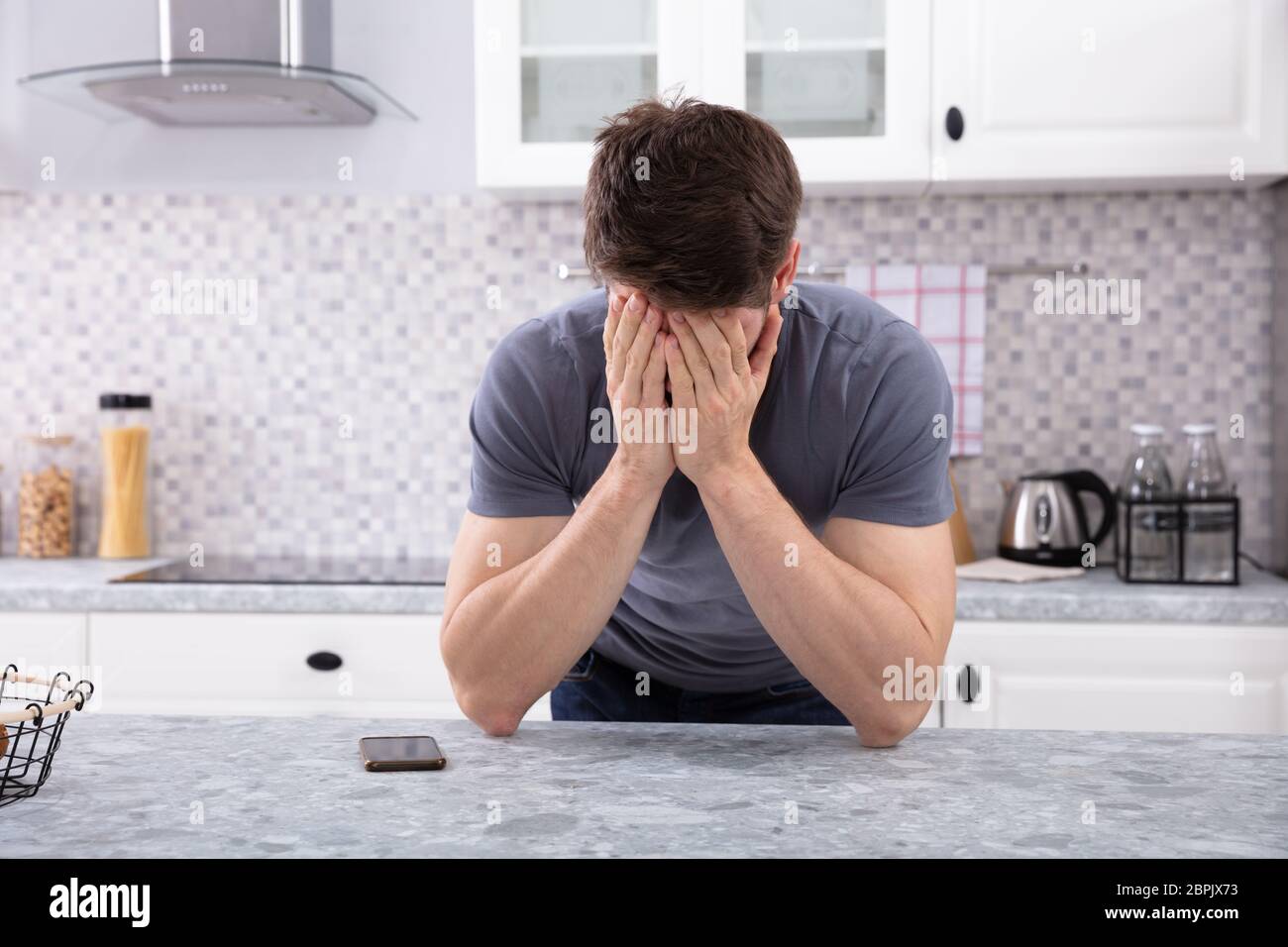 Frustrated Man Covering His Face With Two Hand Sitting In Kitchen Stock ...