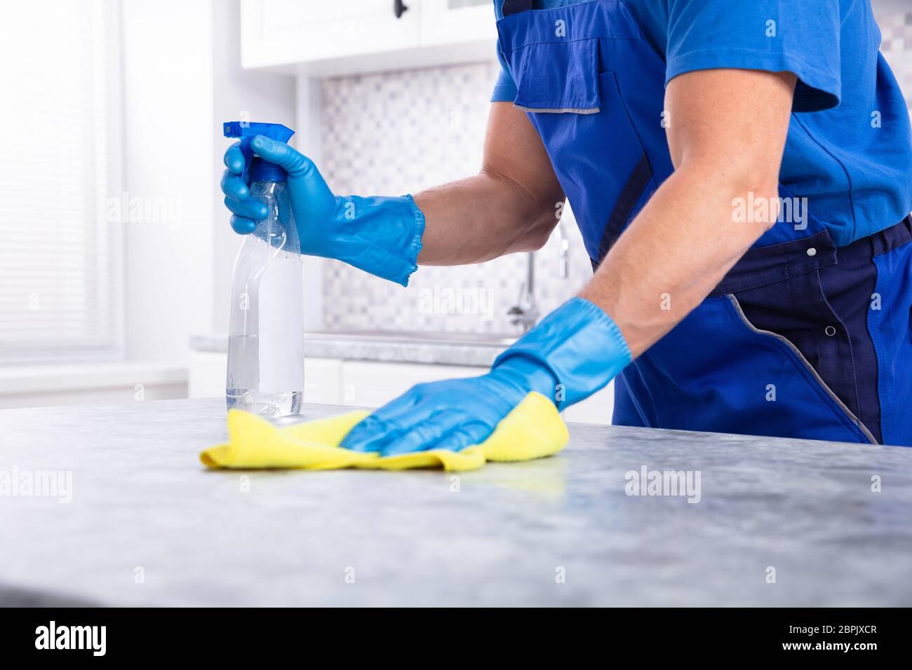 Mid Section Of A Male Janitor Cleaning Dirty Kitchen Counter With Spray ...