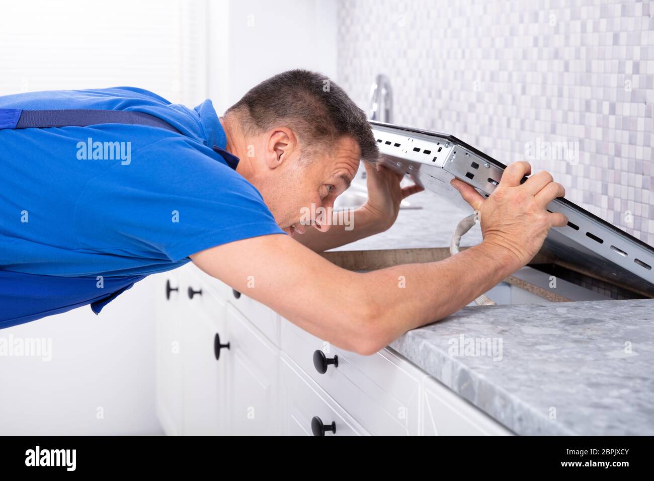 Mature Repairman Installing Induction Stove In Kitchen Stock Photo - Alamy