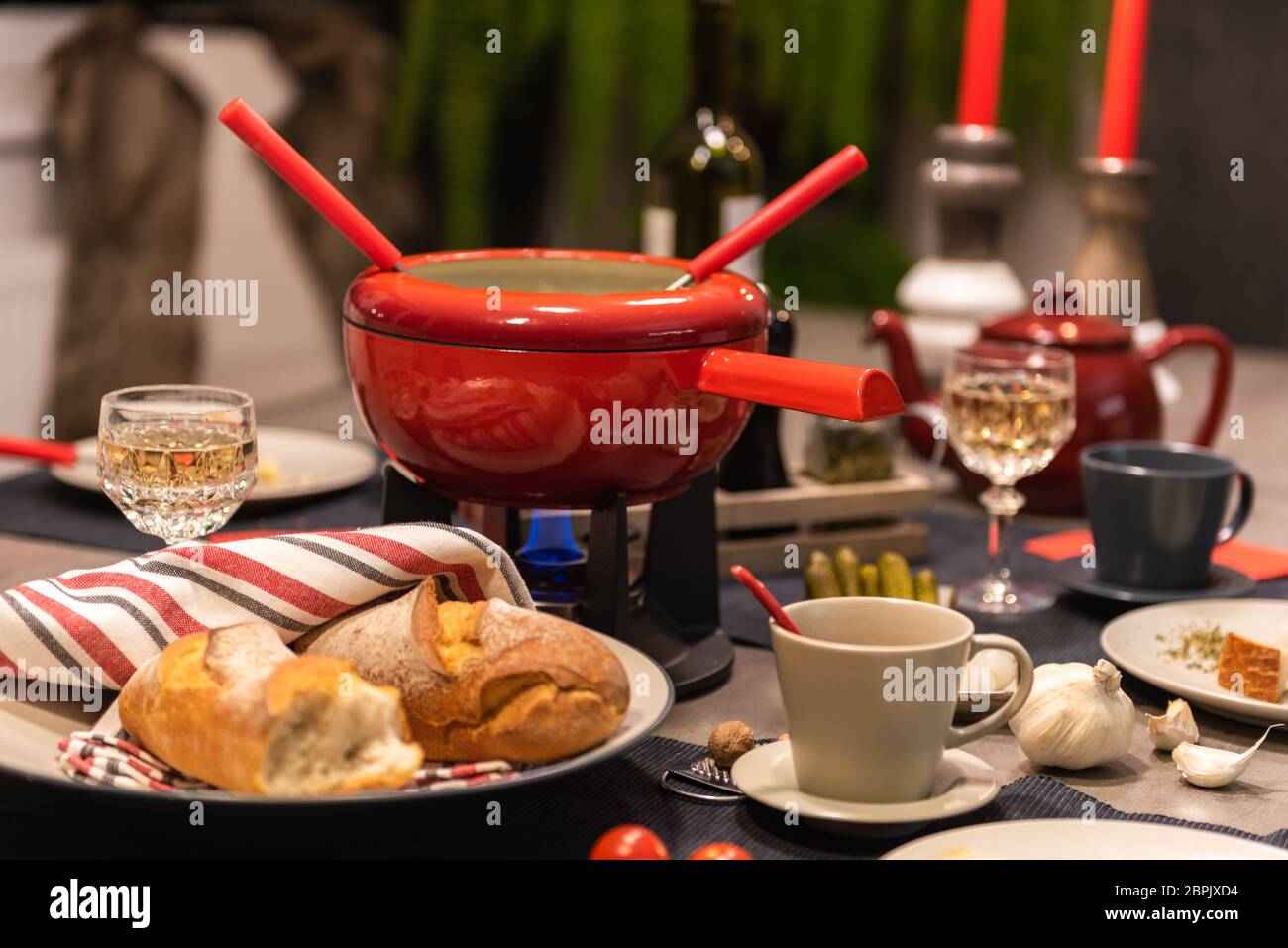 Traditional swiss cheese fondue in a red pot on concrete dining table ...