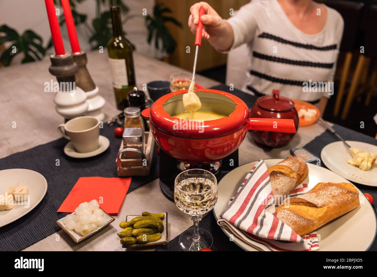 Traditional swiss cheese fondue in a red pot on concrete dining table ...