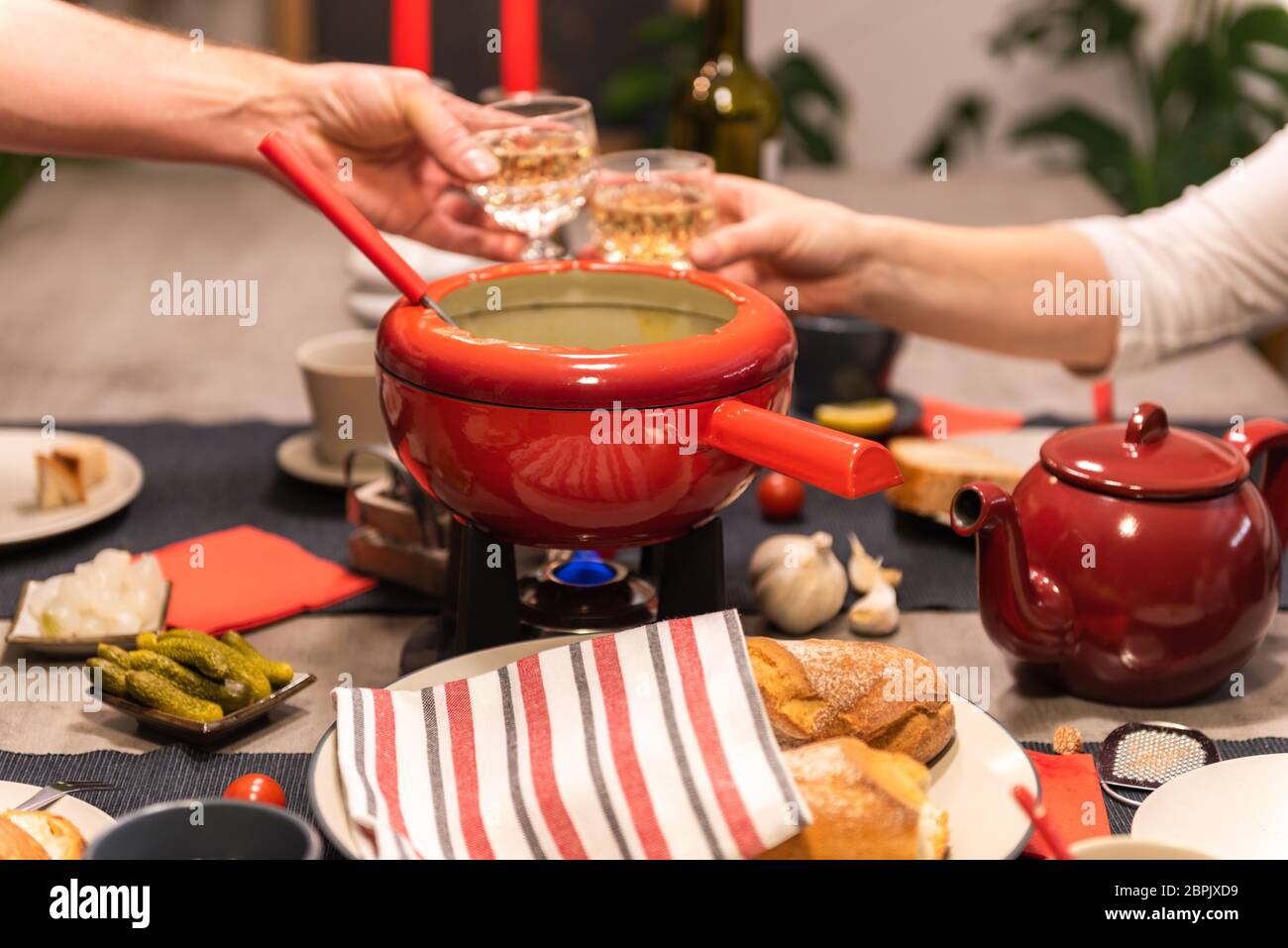 Traditional swiss cheese fondue in a red pot on concrete dining table ...