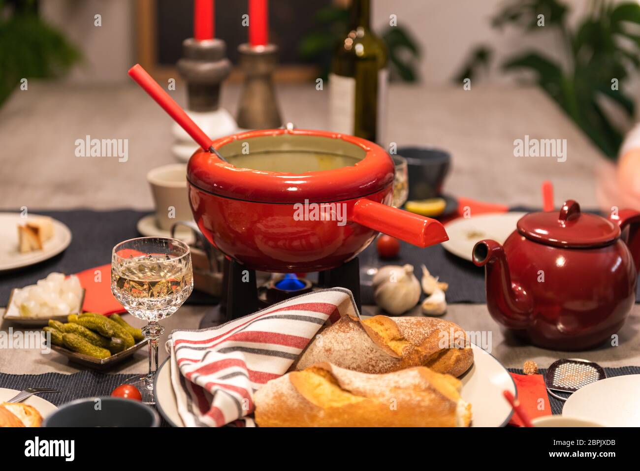 Traditional swiss cheese fondue in a red pot on concrete dining table ...