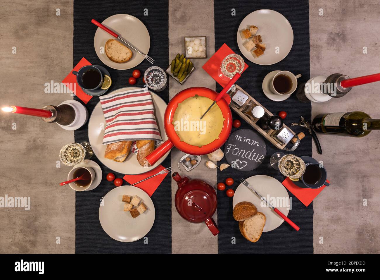Traditional swiss cheese fondue in a red pot on concrete dining table ...