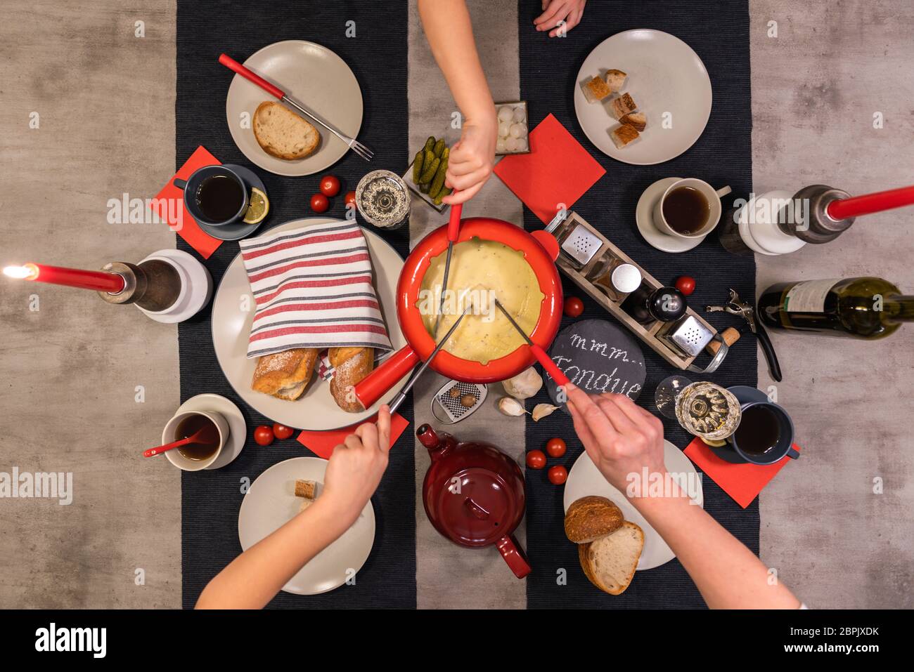 Traditional swiss cheese fondue in a red pot on concrete dining table ...