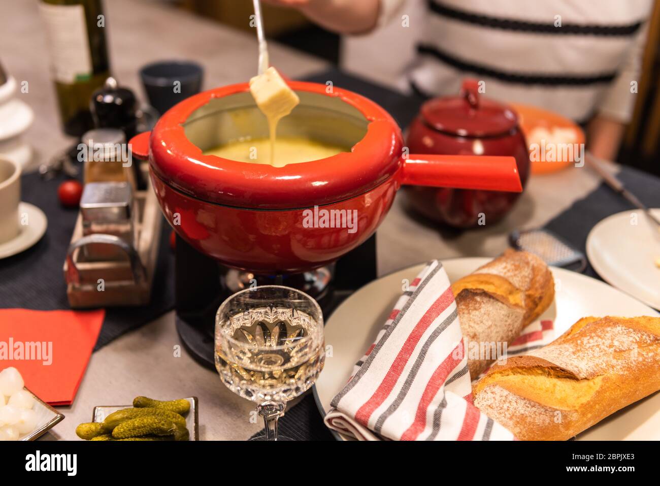 Traditional swiss cheese fondue in a red pot on concrete dining table ...