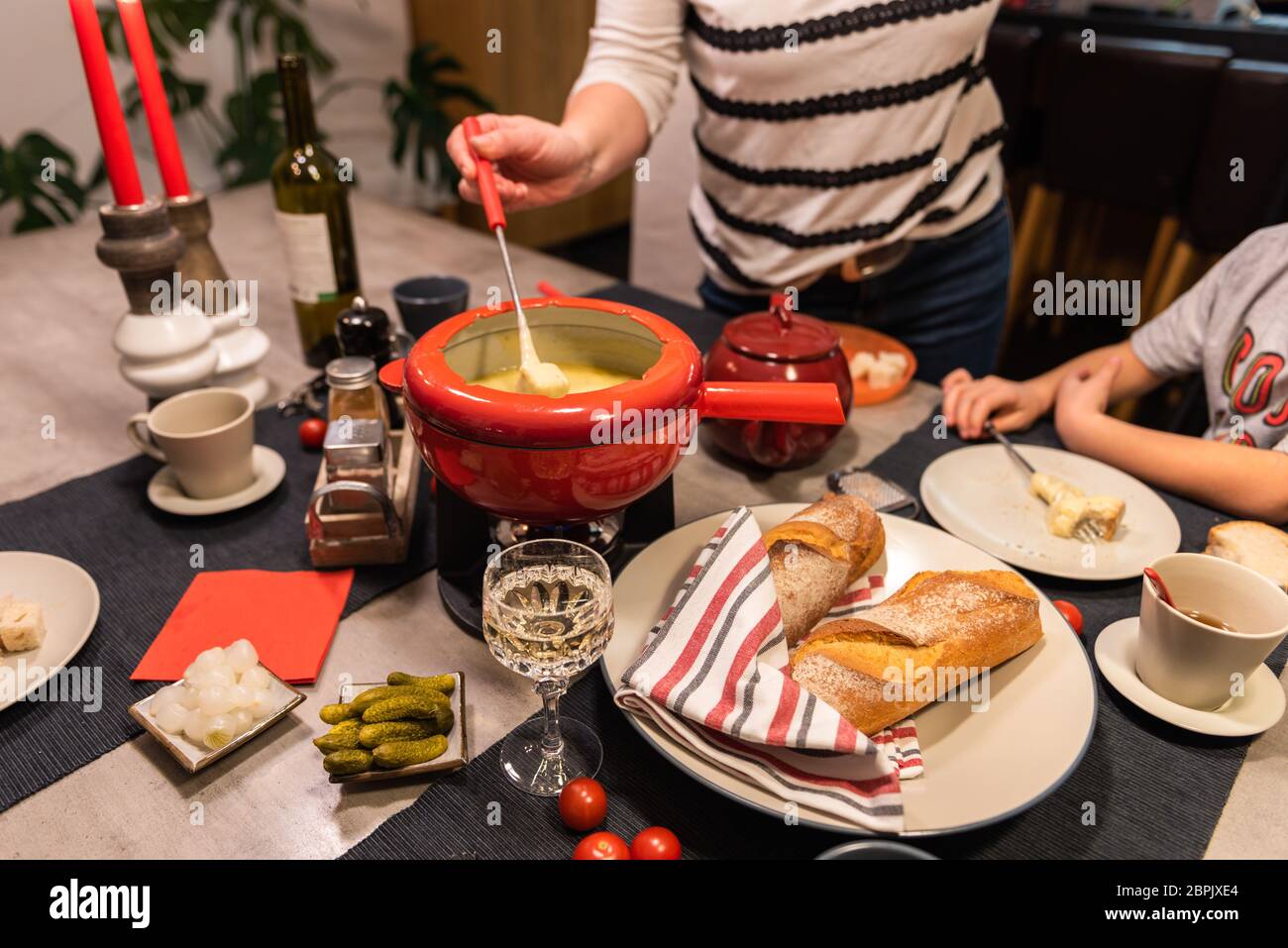 Traditional swiss cheese fondue in a red pot on concrete dining table ...