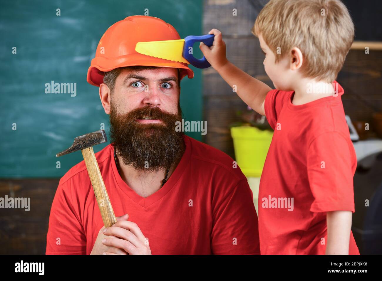 Boy, child cheerful playing with toy saw, learning use tools with dad ...