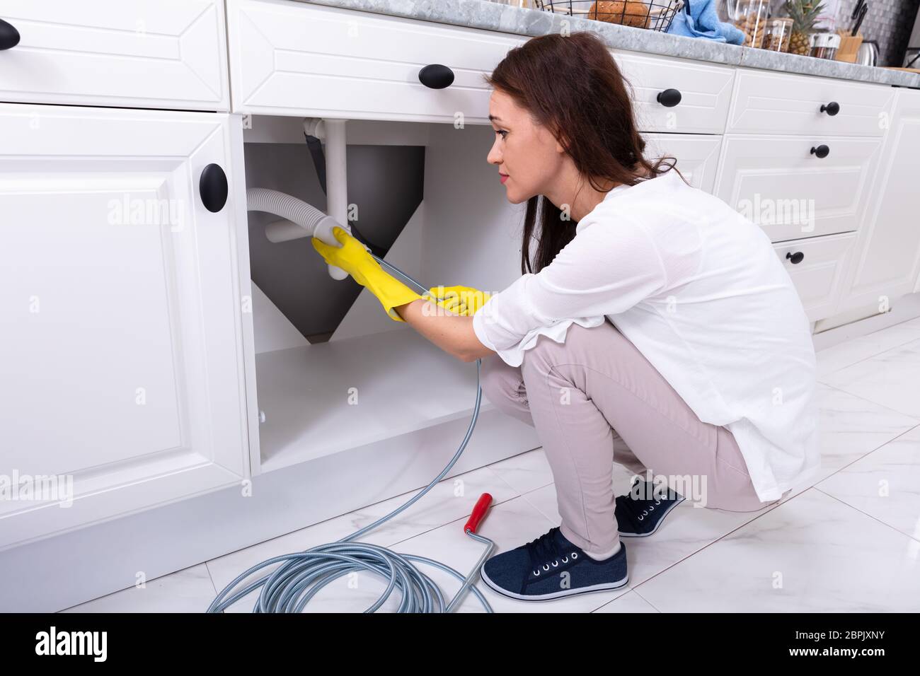 Side View Of A Young Woman Cleaning Clogged Sink Pipe In Kitchen Stock ...