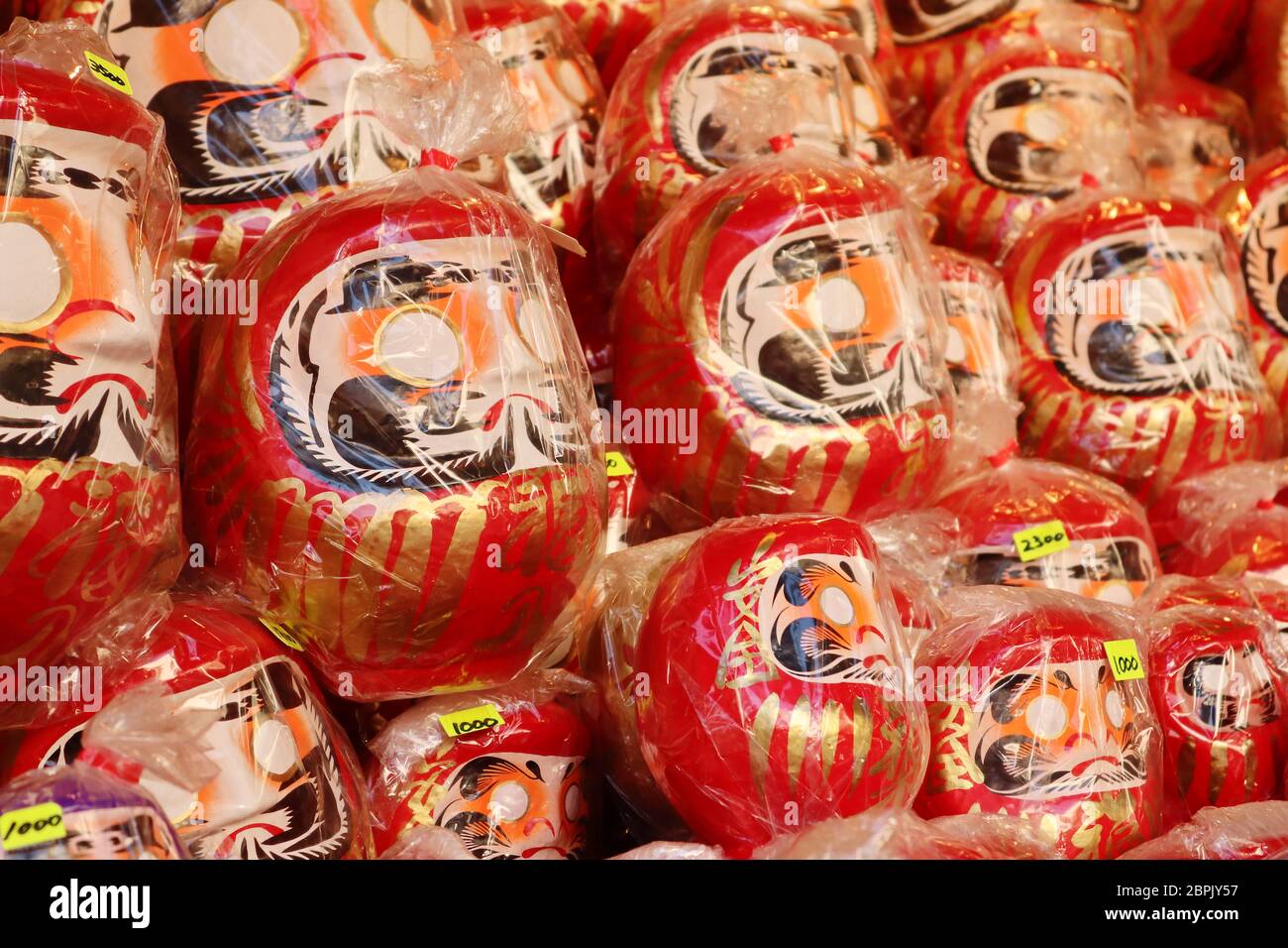 Red dharma tumbling dolls lining up at a storefront Stock Photo - Alamy