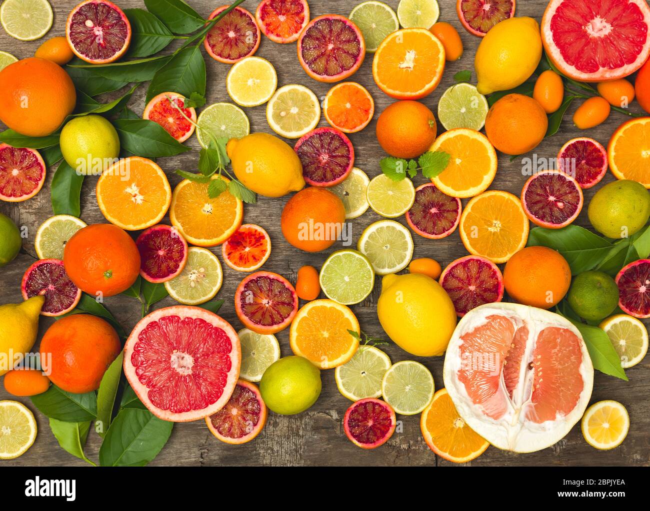 many different juicy and healthy citrus fruits lie together on an old ...