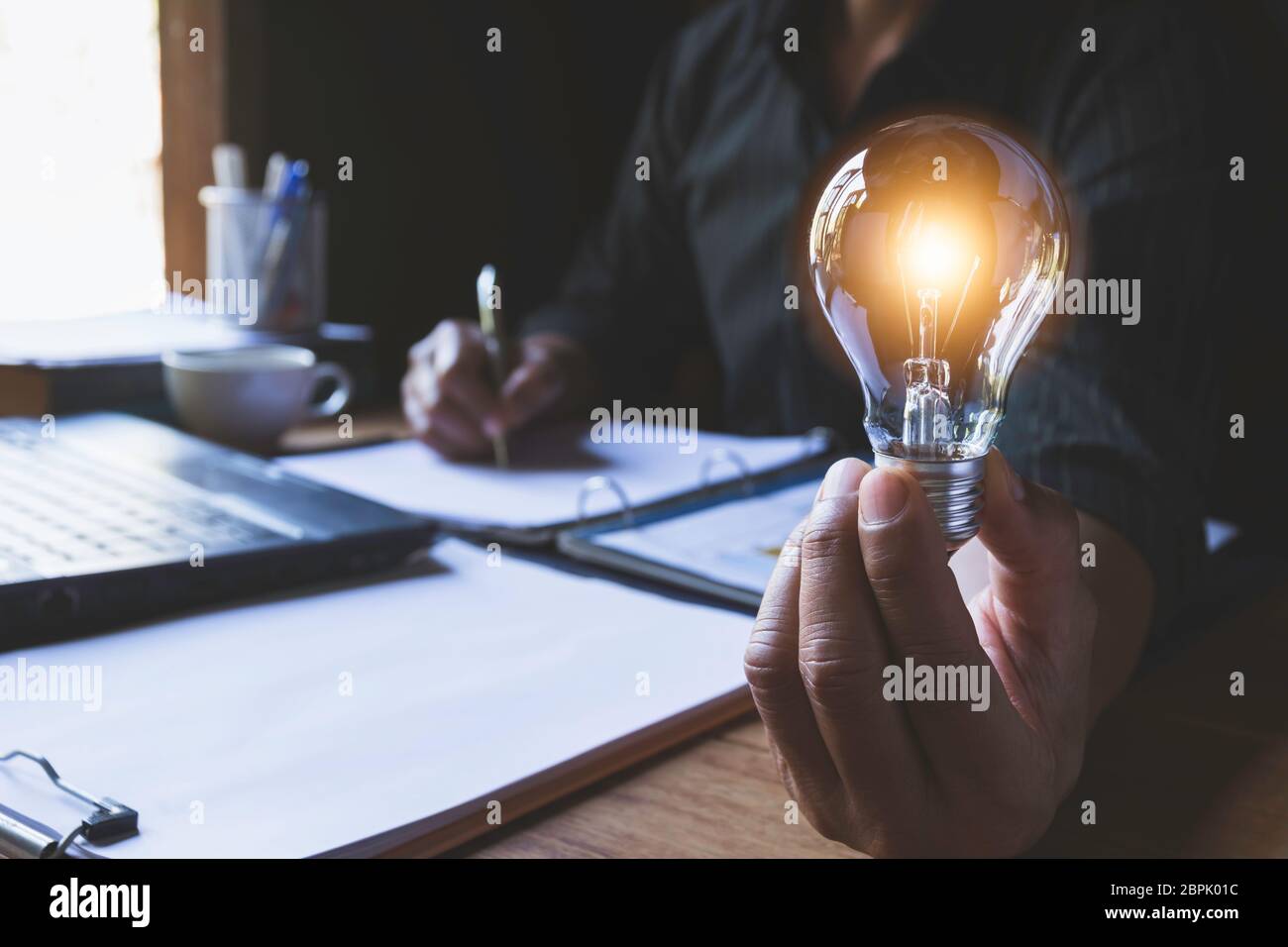 Hand of male holding a light bulb and writing for idea and creative ...