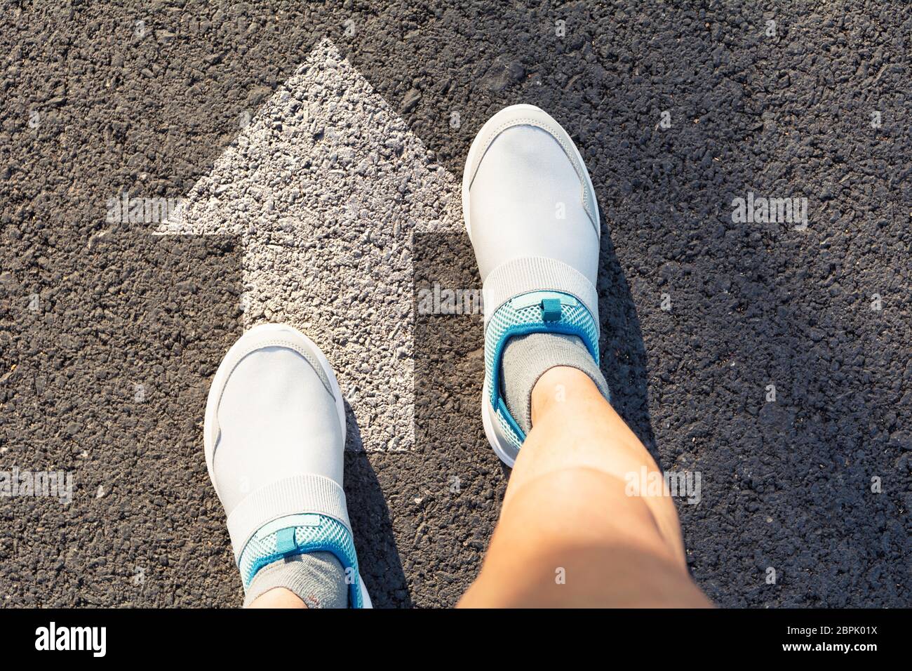 Top view of man wearing white shoes choosing a way marked with white ...