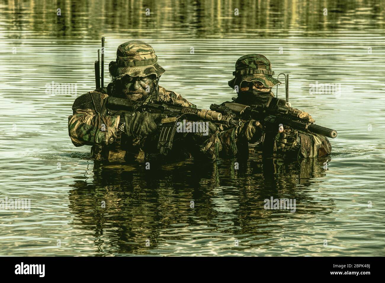 Pair of soldiers in action during river raid in the jungle waist deep ...