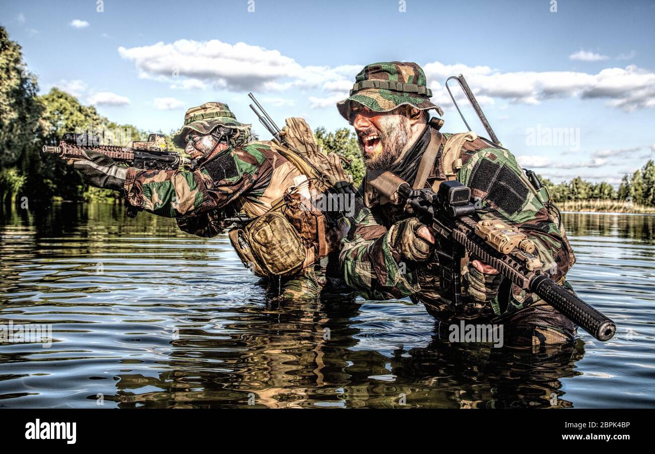 Pair of soldiers in action during river raid in the jungle waist deep ...