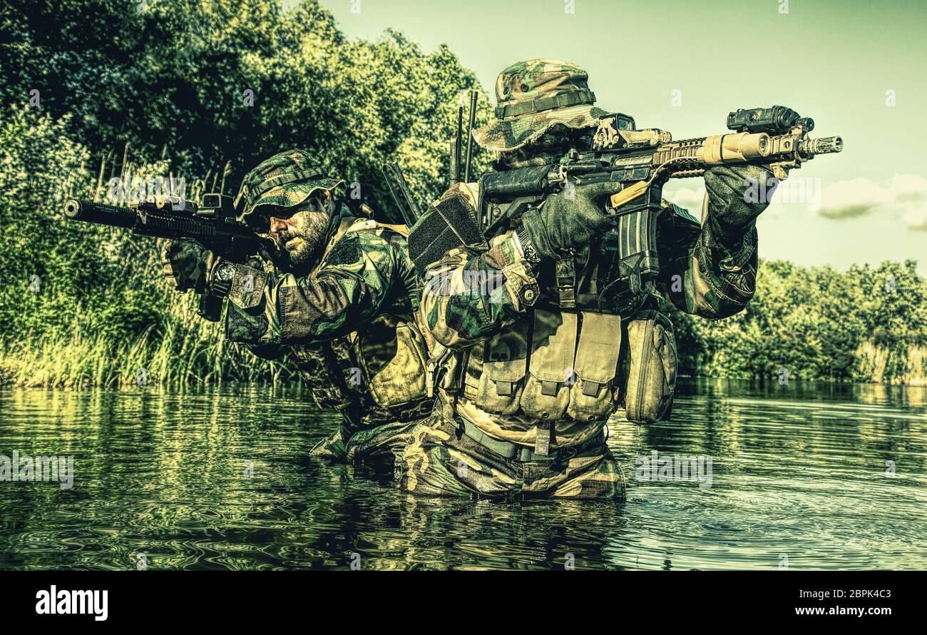 Pair of soldiers in action during river raid in the jungle waist deep ...