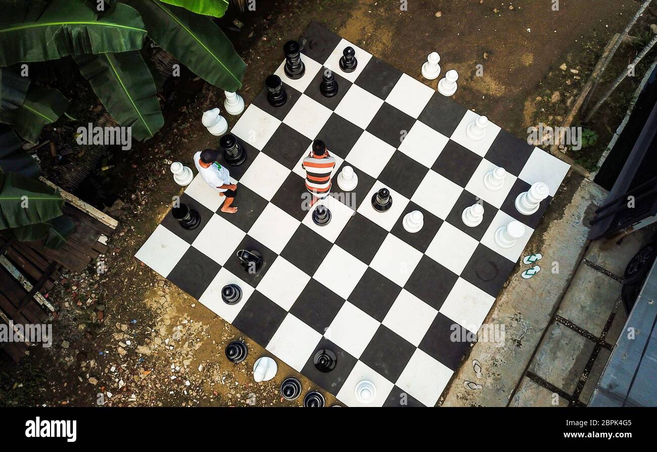 People playing giant chess in a backyard of a village house.Chess is a ...