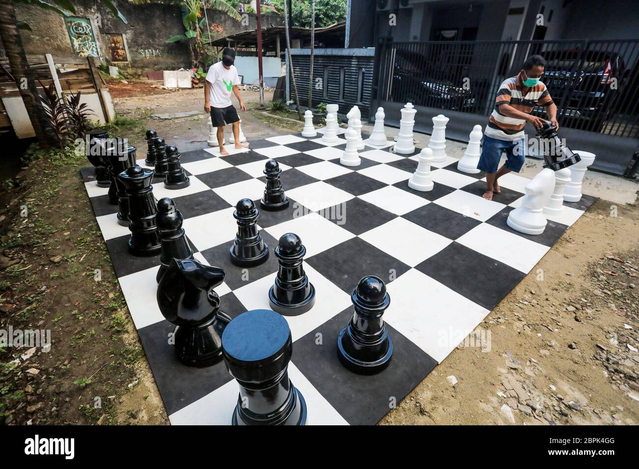 People playing giant chess in a backyard of a village house.Chess is a ...