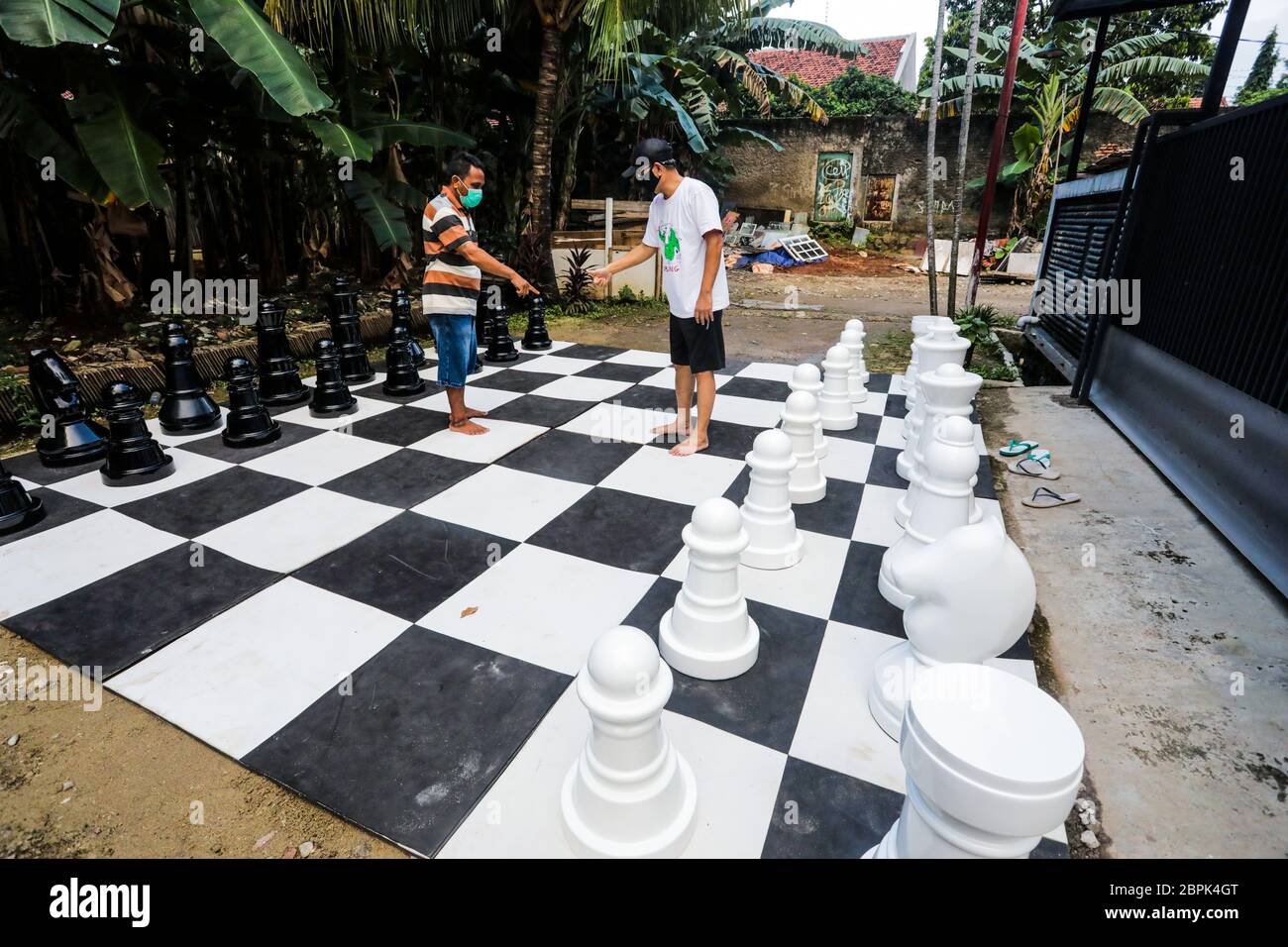 People playing giant chess in a backyard of a village house.Chess is a ...