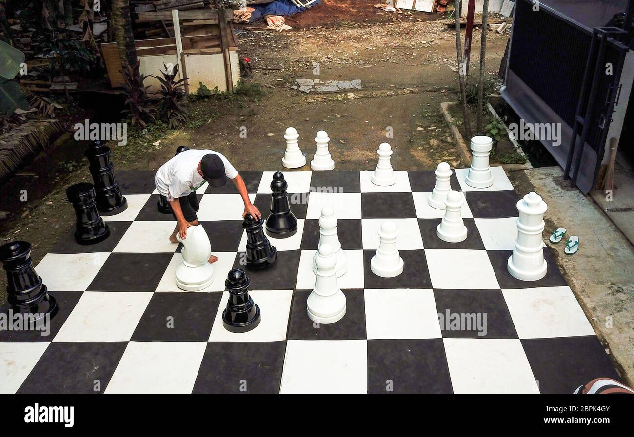 People playing giant chess in a backyard of a village house.Chess is a ...