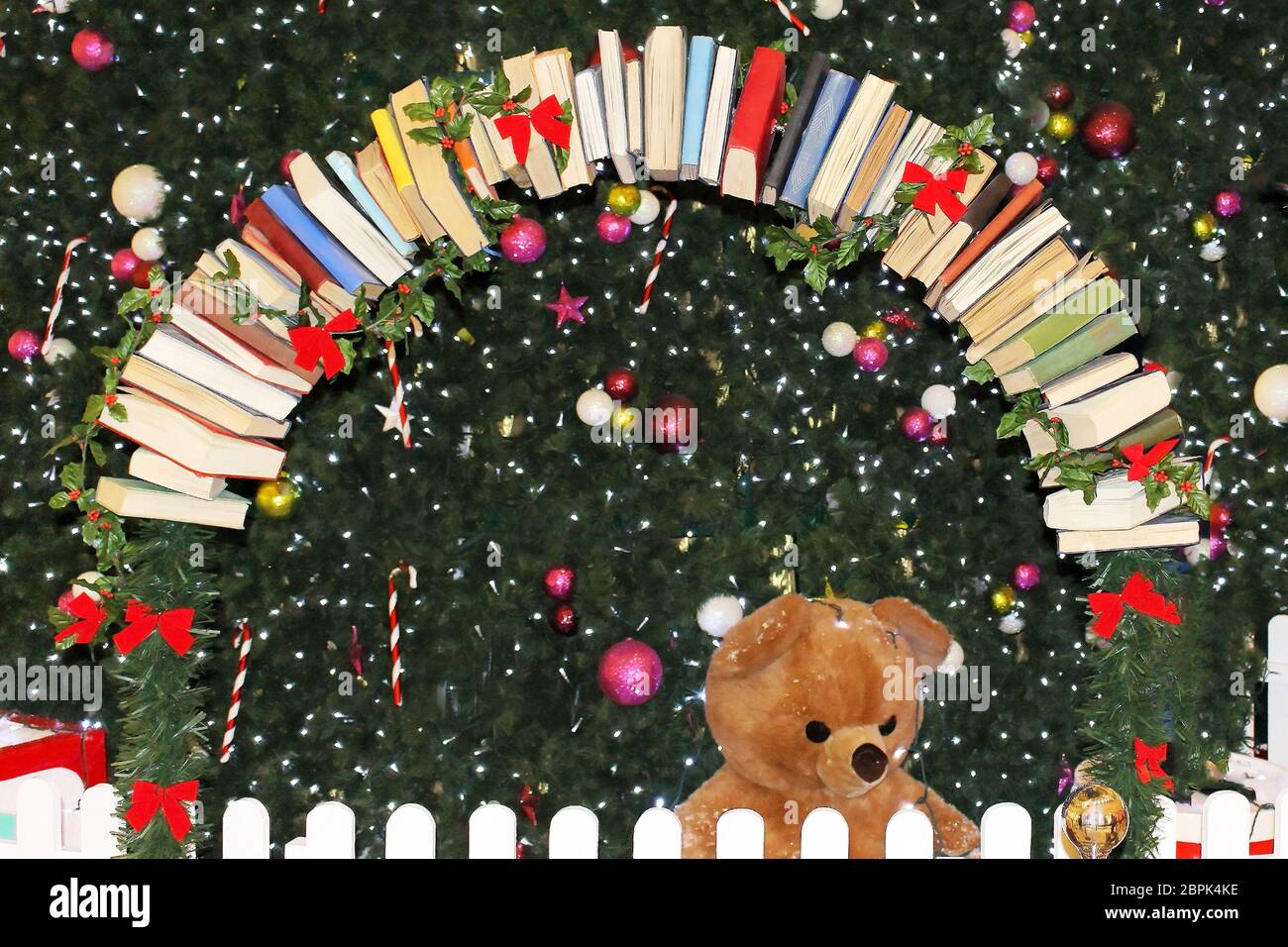 Row of books as ornament on decorated Christmas tree with red bows and ...