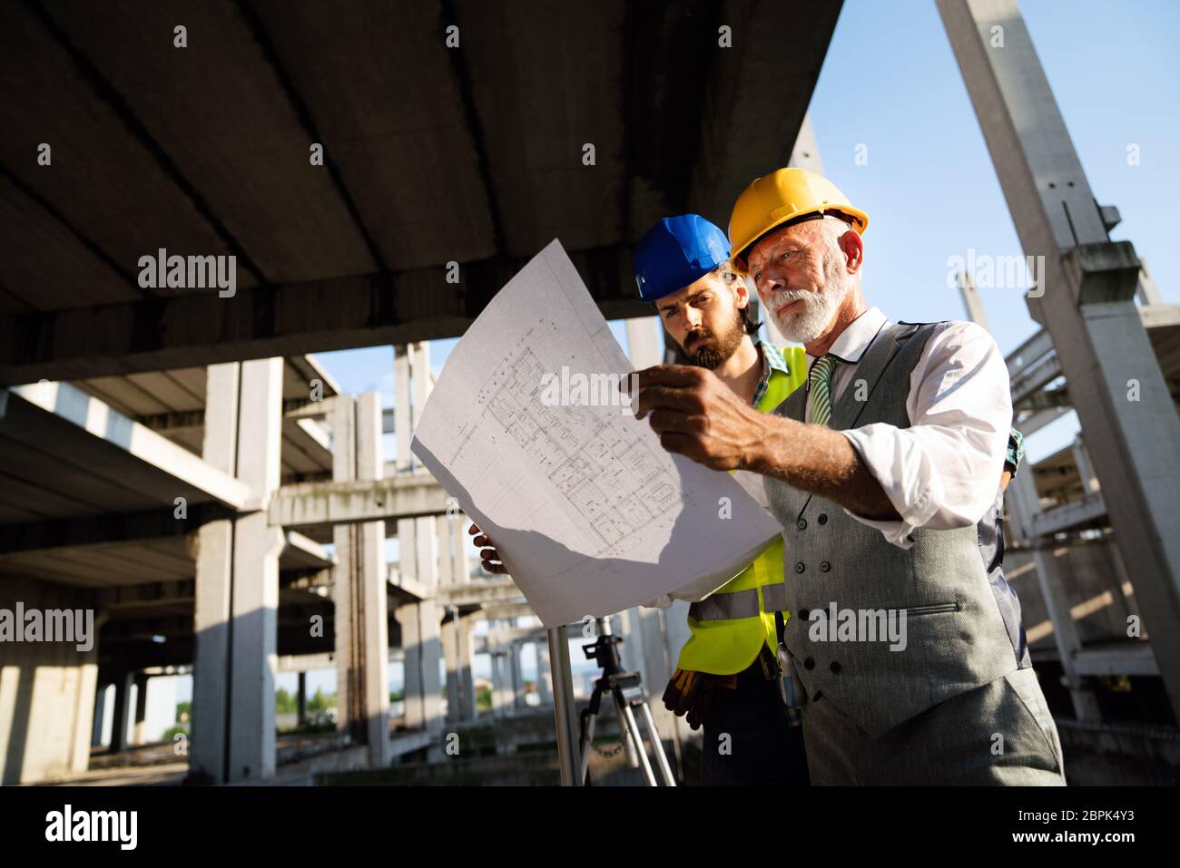 Male architects analyzing blueprint at construction site Stock Photo ...