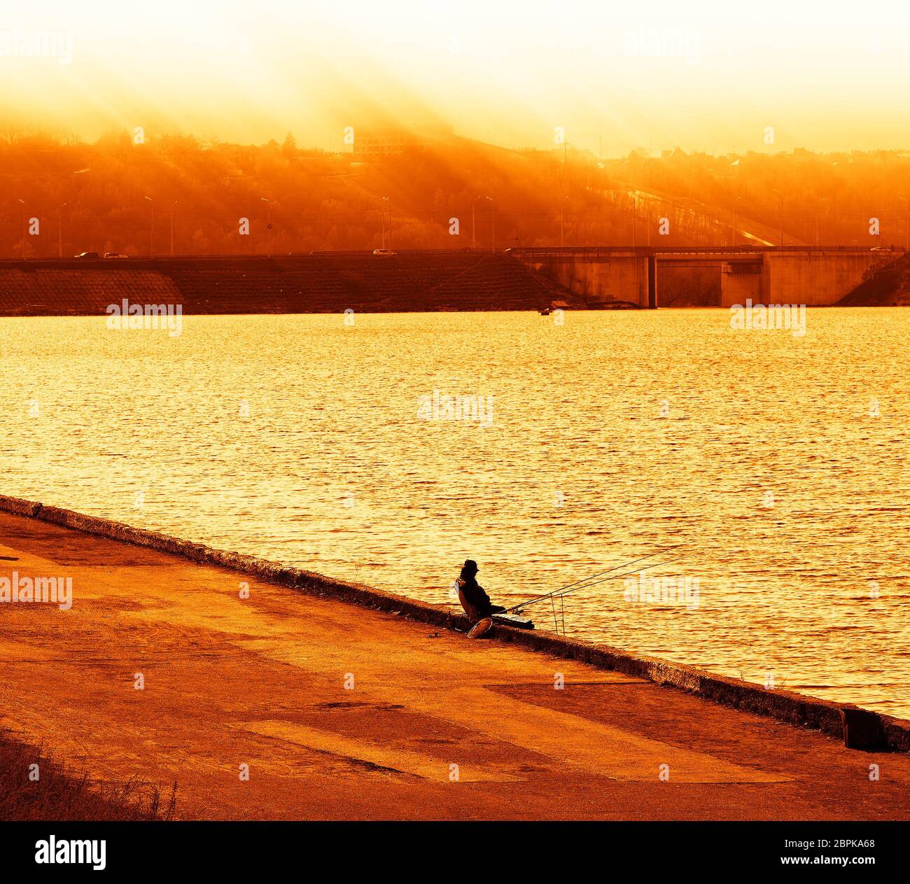 Fisherman on sunset river bank background Stock Photo - Alamy