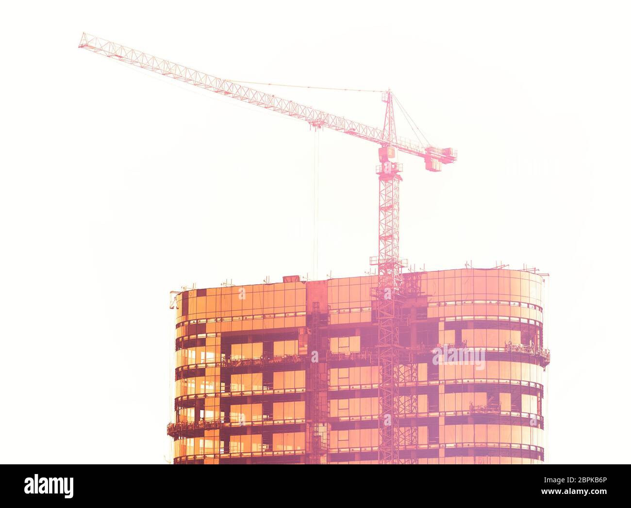 Construction crane building skyscraper during sunset Stock Photo - Alamy