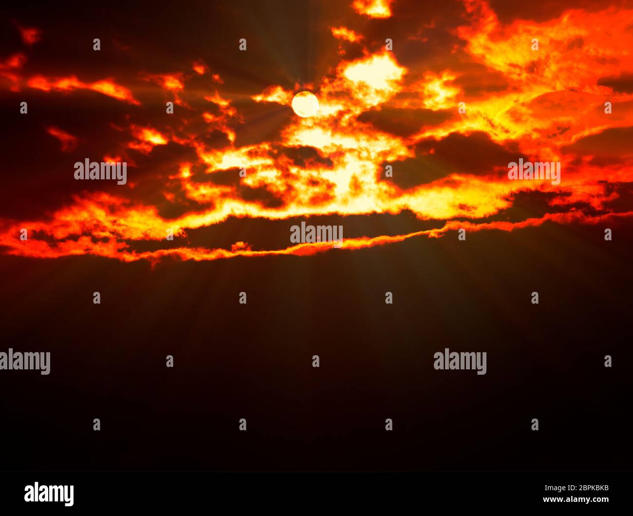 Sunset light rays with dark clouds background Stock Photo - Alamy