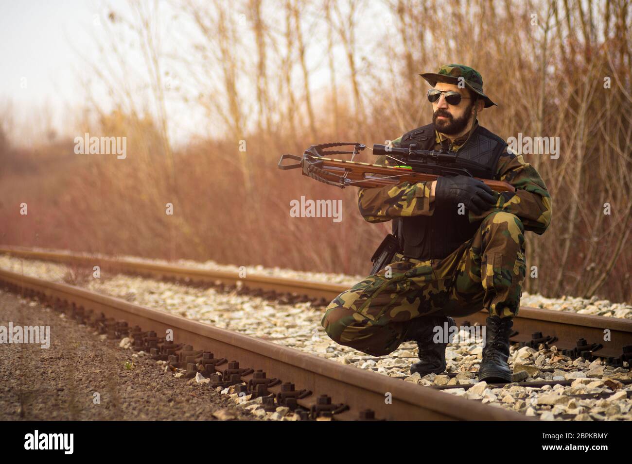 The army soldier in military uniform with crossbow weapon is on ...